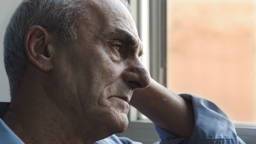Sad Old Man Sitting Alone Near A Window And Thinking About Something