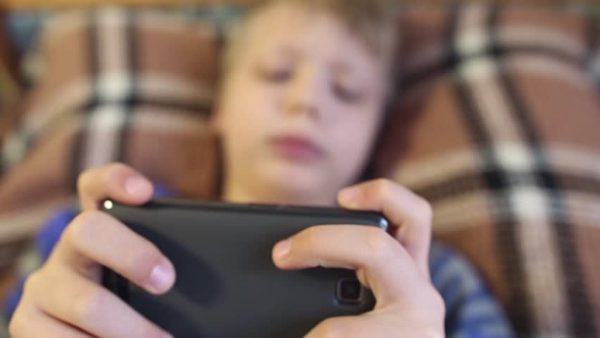 8 Years Old Kid Playing Computer Games While Laying In His Bed In ...