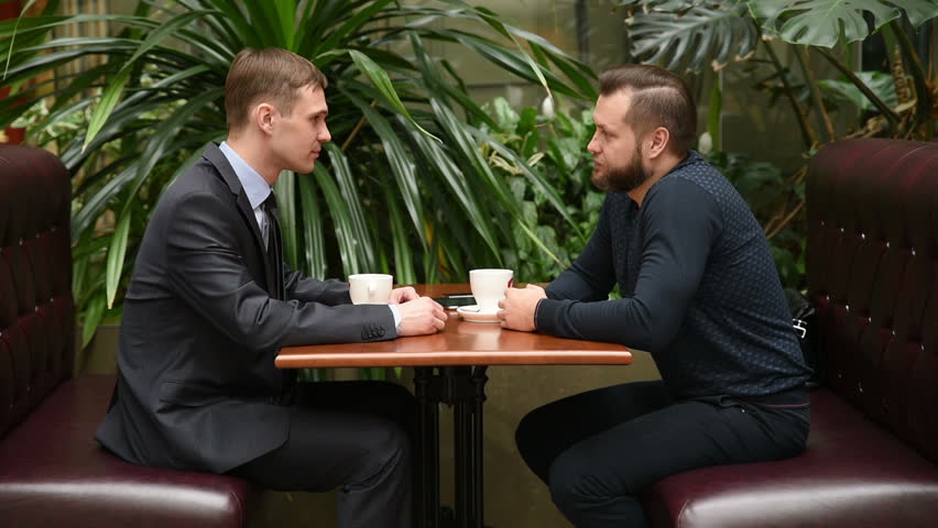Two Businessmen Sitting At A Table, They Have A Business Meeting. One ...