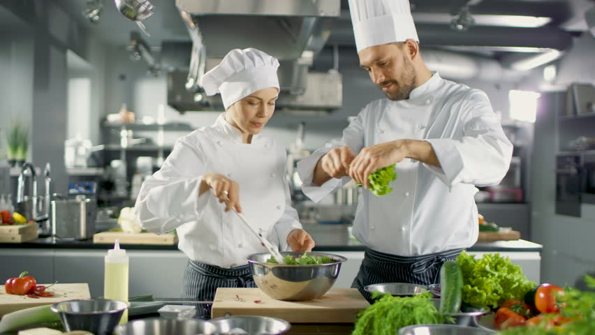Chef Slicing Vegetables On A Green Board In A Commercial Kitchen Stock ...