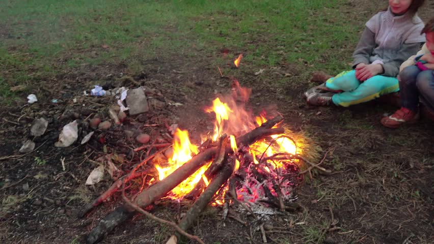 Two Little Beautiful Girls Are Sitting By Fire In Evening Forest. Stock ...